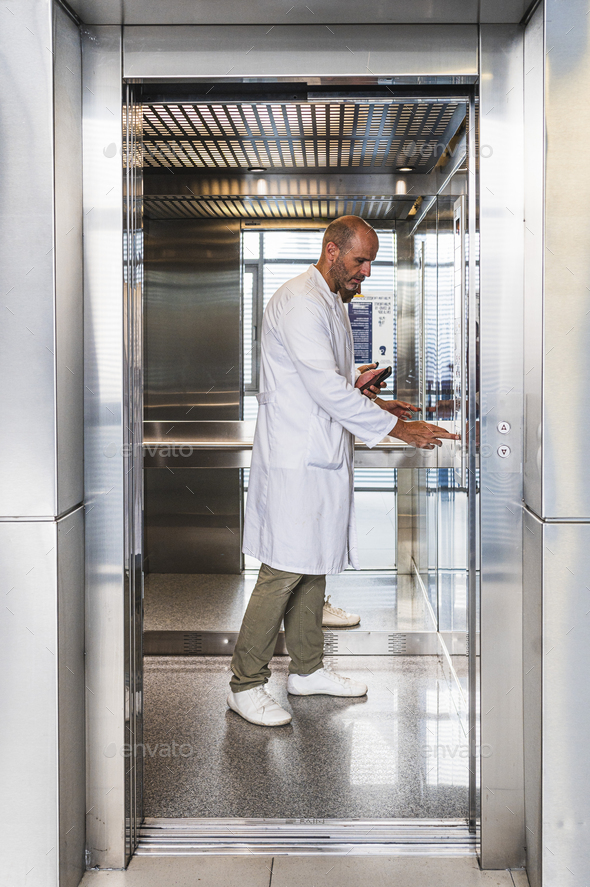 Gown-clad scientist pressing buttons inside an elevator. Stock Photo by ...