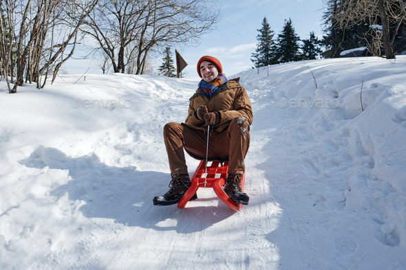 Joyful Young Man Sledding Stock Photo by Pressmaster | PhotoDune