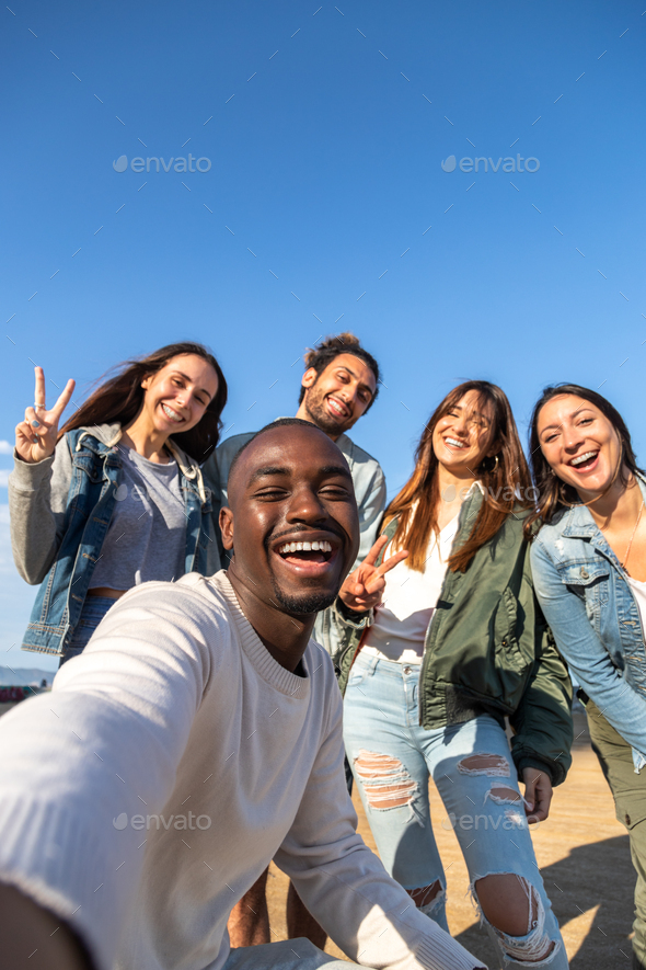 Smiling multiracial friends take selfie looking at camera. Copy space. Vertical image. Stock ...