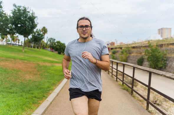 White man with long hair running in park and smiling. Sport Concept ...