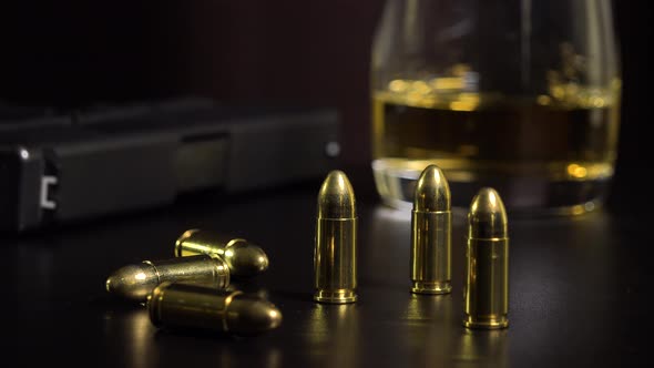 Closeup on Bullets on a Black Table - a Gun and a Glass of Whiskey in ...