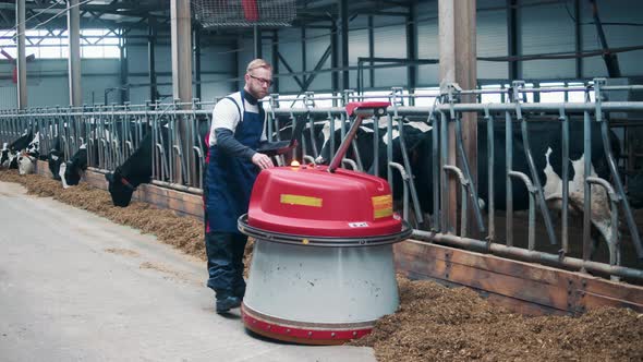 Male Worker is Operating a Robotic Feed Pusher in a Cowshed, Stock Footage