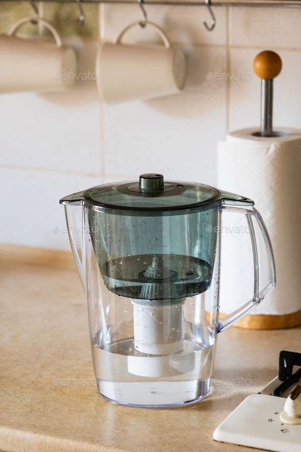 Water filter jug on kitchen table. Clean water concept. Filtration ...