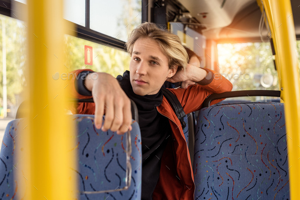thoughtful man sitting on bus seat while riding in public transport ...