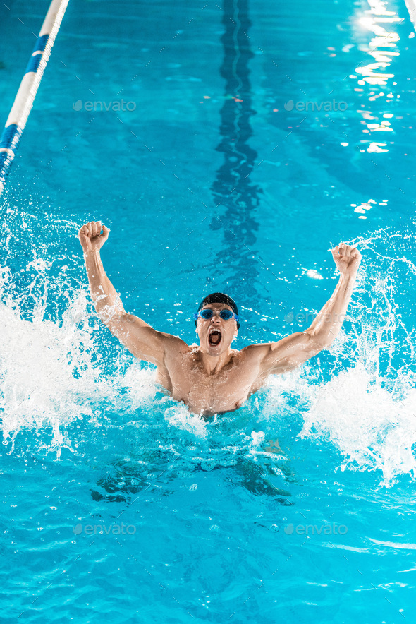 excited swimmer gesturing and making splash in competition swimming ...