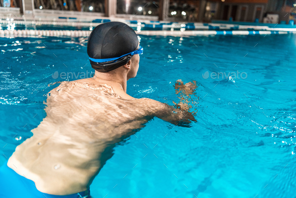 back view of swimmer in swimming cap and goggles swimming in pool Stock ...