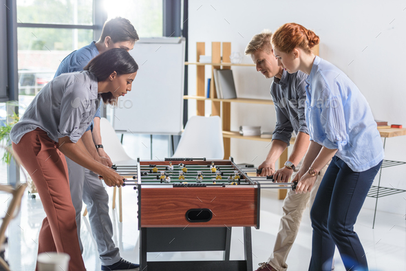 Colleagues playing table football in modern office Stock Photo by ...