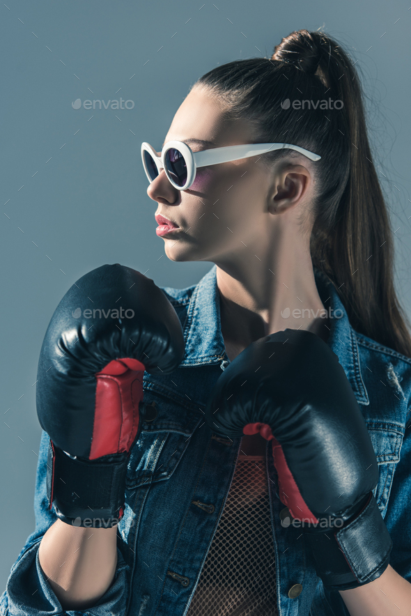 stylish girl in denim and sunglasses posing with boxing gloves ...