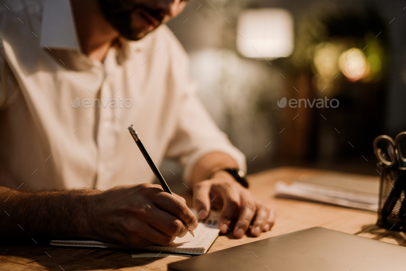 White man writing down notes in planner while working at office Stock ...