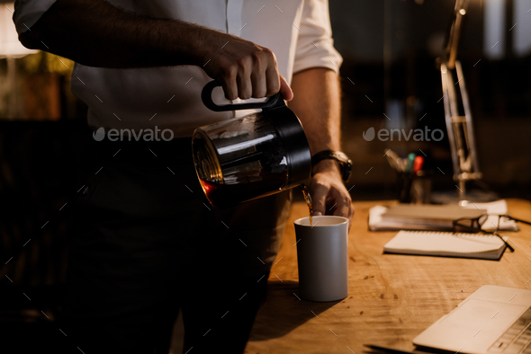 White man drinking coffee while working in evening Stock Photo by ...