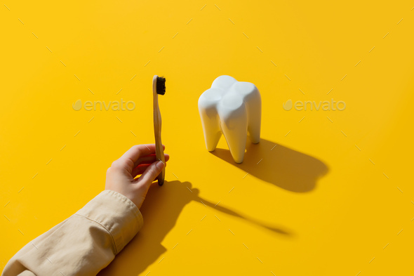 female hand brushing a tooth on yellow background Stock Photo by Masson ...