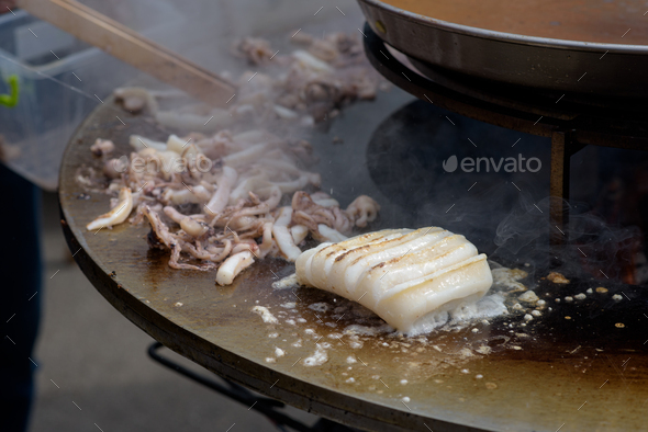 Octopus meat is prepared at the street food festival with smoke and ...