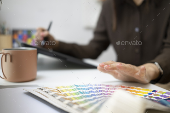 Close up view of graphic designer choosing colors from color swatch ...