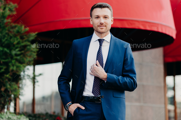 Handsome male company owner dressed formally, stands outside, has ...
