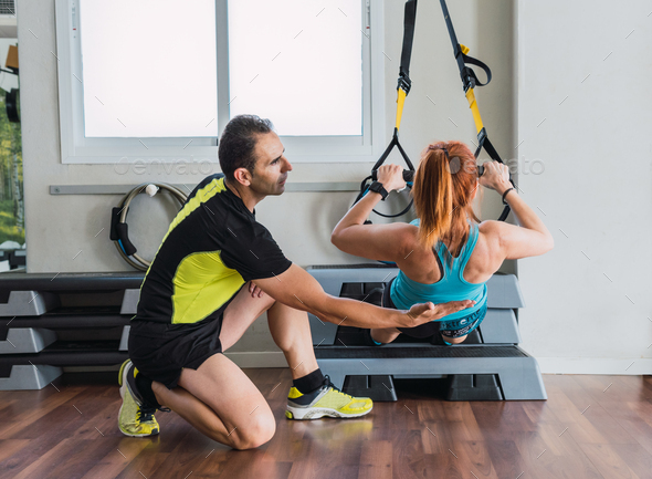 Coach helping a woman to do exercises with a trx Stock Photo by ...