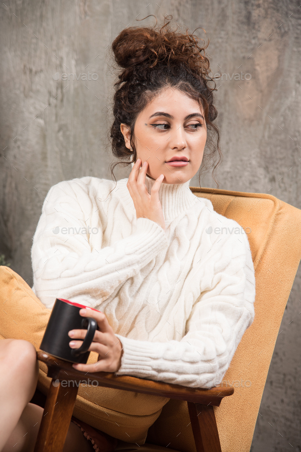 Photo of pensive woman sitting in comfy chair with a cup of drink Stock ...
