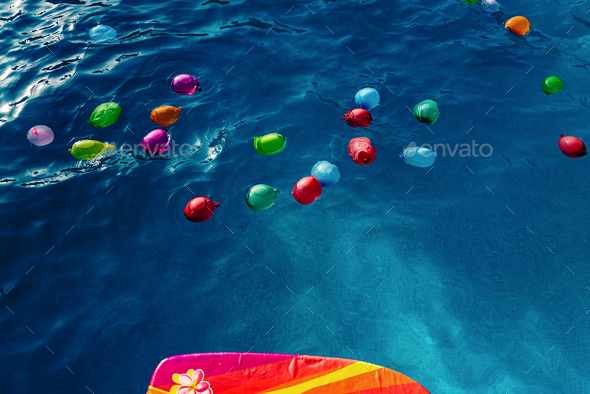 Group of many colorful plastic water balloons floating in the water of ...
