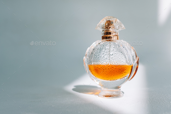 Perfume bottle with water drops on white background in sunlight. Stock ...