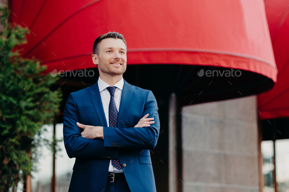 Male CEO in formal suit stands crossed hands, looks with satisfied ...