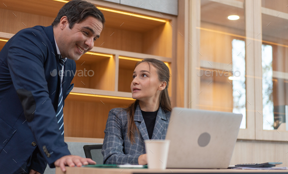 Male manager watching project on laptop with female assistant Stock ...