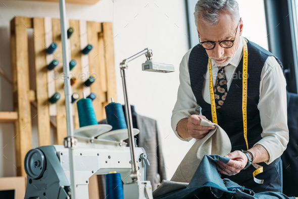 handsome tailor choosing between dark and light clothes at sewing ... handsome tailor choosing between dark and light clothes at sewing ...