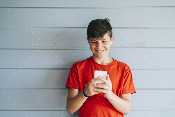 Profile of a happy male teen texting on a smart phone Stock Photo by ...