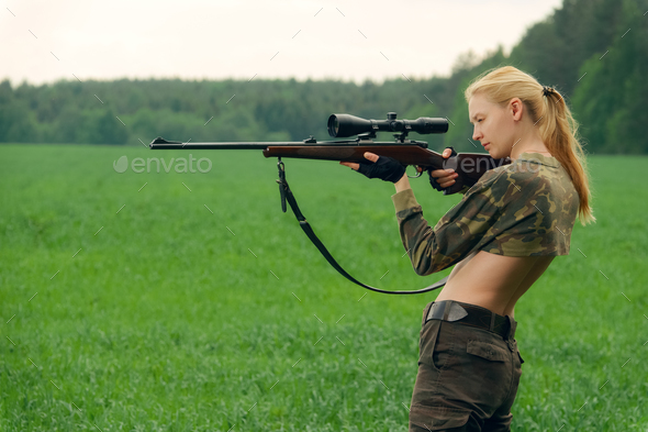 Pretty hunter girl aiming with hunting rifle in the outer wood. Carbine ...