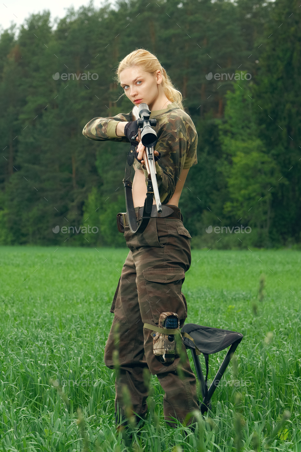 Pretty hunter girl aiming with hunting rifle in the outer wood. Carbine ...