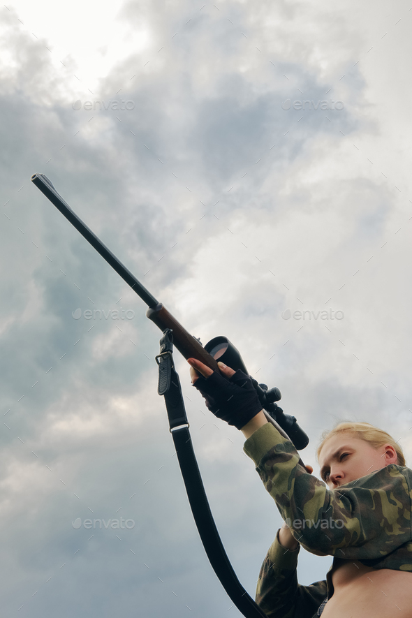 Pretty hunter girl aiming with hunting rifle in the outer wood. Low ...