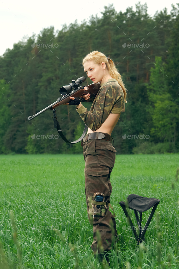 Pretty hunter girl aiming with hunting rifle and ready to shoot ...