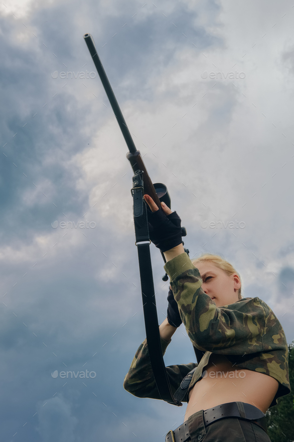Pretty hunter girl aiming with hunting rifle in the outer wood. Low ...