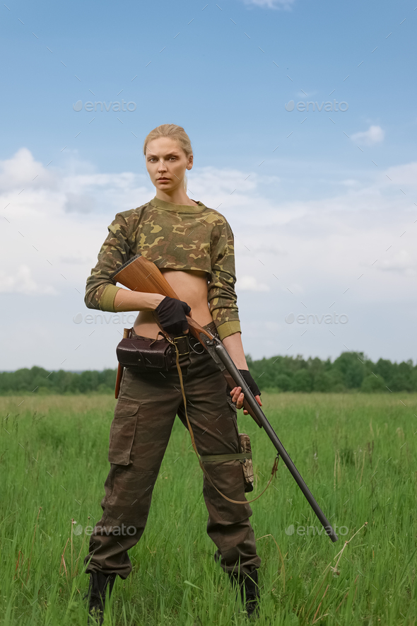 Attractive hunter girl with hunting double-barreled rifle looking out ...