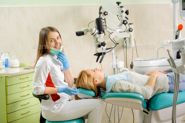 Female dentist treating caries using microscope at the dentist office ...