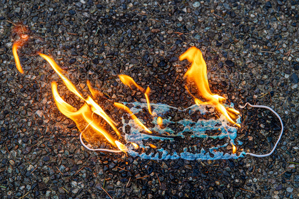 Medical mask burning on the ground to represent the end of the Covid-19 ...