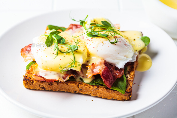 Eggs benedict on toast with bacon and traditional hollandaise sauce ...