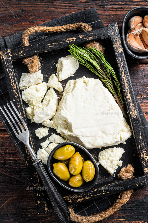 French Goat soft cheese in a tray with olives and rosemary. Wooden ...