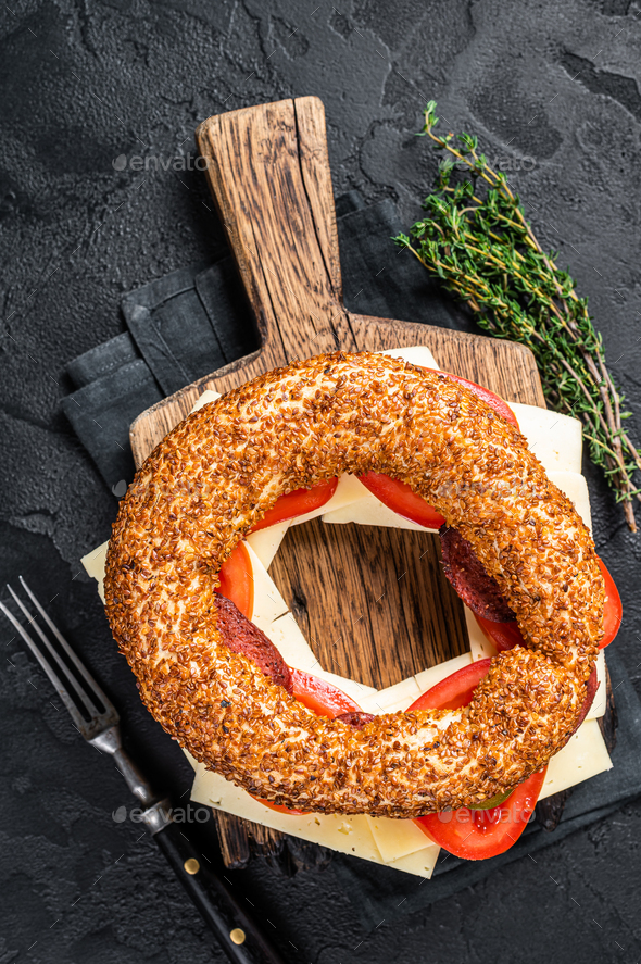 Simit bagel sandwich with lettuce, tomato, yellow cheese and ham. Black ...