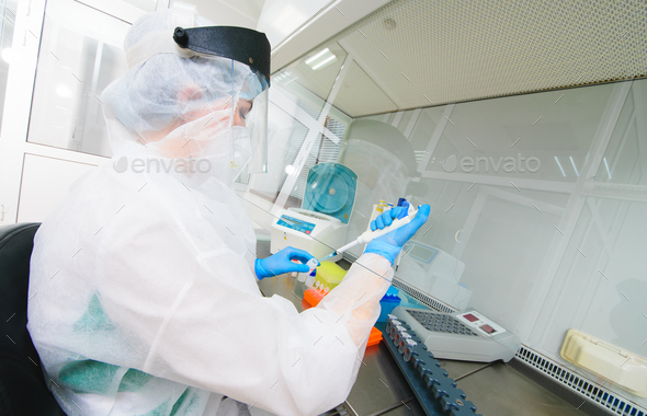PCR laboratory worker conducts research in a protective suit and helmet ...