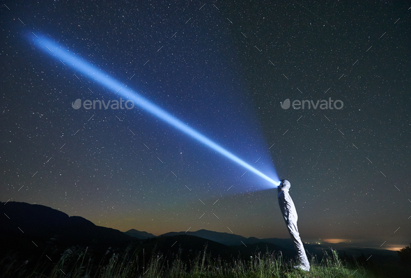 Space traveler shining flashlight into beautiful starry sky. Stock ...