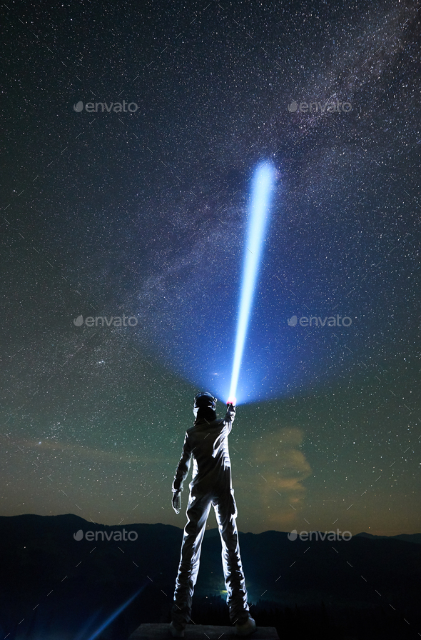 Cosmonaut shining flashlight into magnificent night sky. Stock Photo by ...