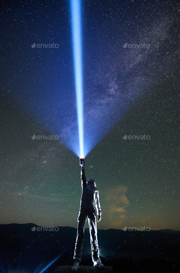 Cosmonaut shining flashlight into magnificent night sky. Stock Photo by ...