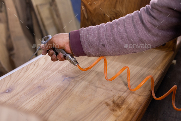 Man blowing dust off the surface of wooden table in the workshop Stock ...