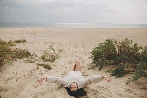 Beautiful woman lying on sandy beach on background of green grass and ...