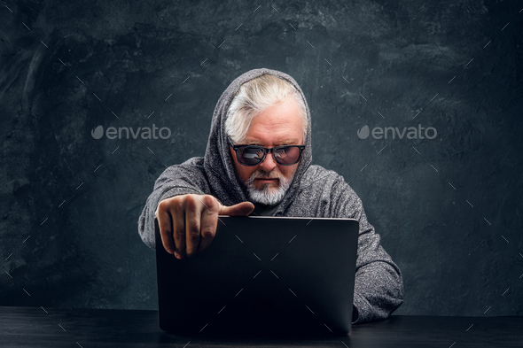 Old man hacker with laptop against dark background Stock Photo by fxquadro