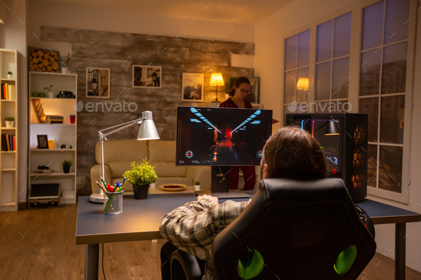 Back view of professional video gamer playing on powerful PC late at ...