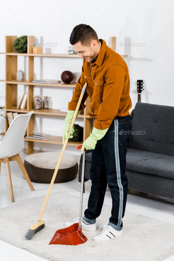 handsome man standing in modern living room and sweeping floor Stock ...
