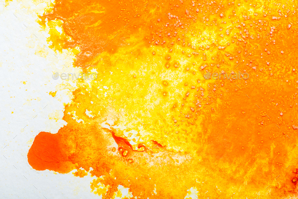 top view of yellow and orange watercolor spills on white paper with ...