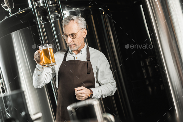 senior brewer examining beer in glass in brewery Stock Photo by ...