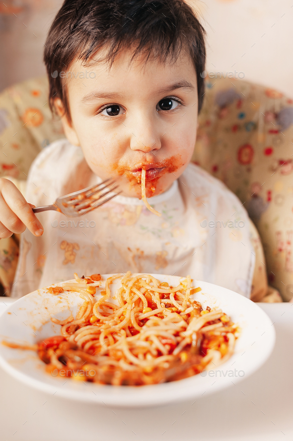 Child eating spaghetti with vegetables. Kid having fun eating. Stock ...