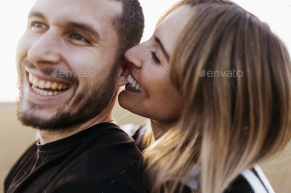 Close up women biting man ear in the countryside embraced. Boyfriend ...